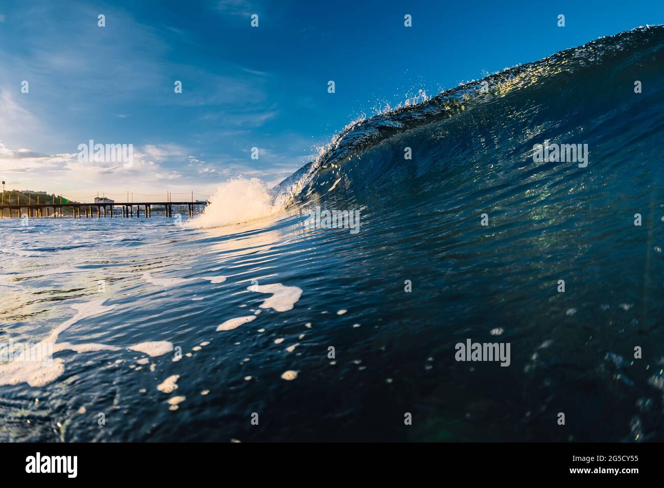 Crashing surfing wave in ocean with warm tones at sunrise or sunset ...
