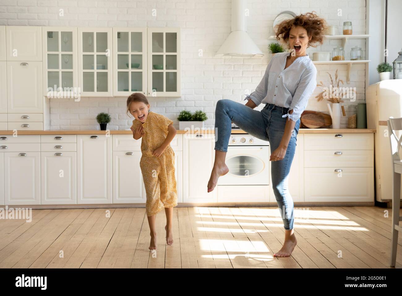 Overjoyed young mother dancing barefoot with cute daughter Stock Photo ...