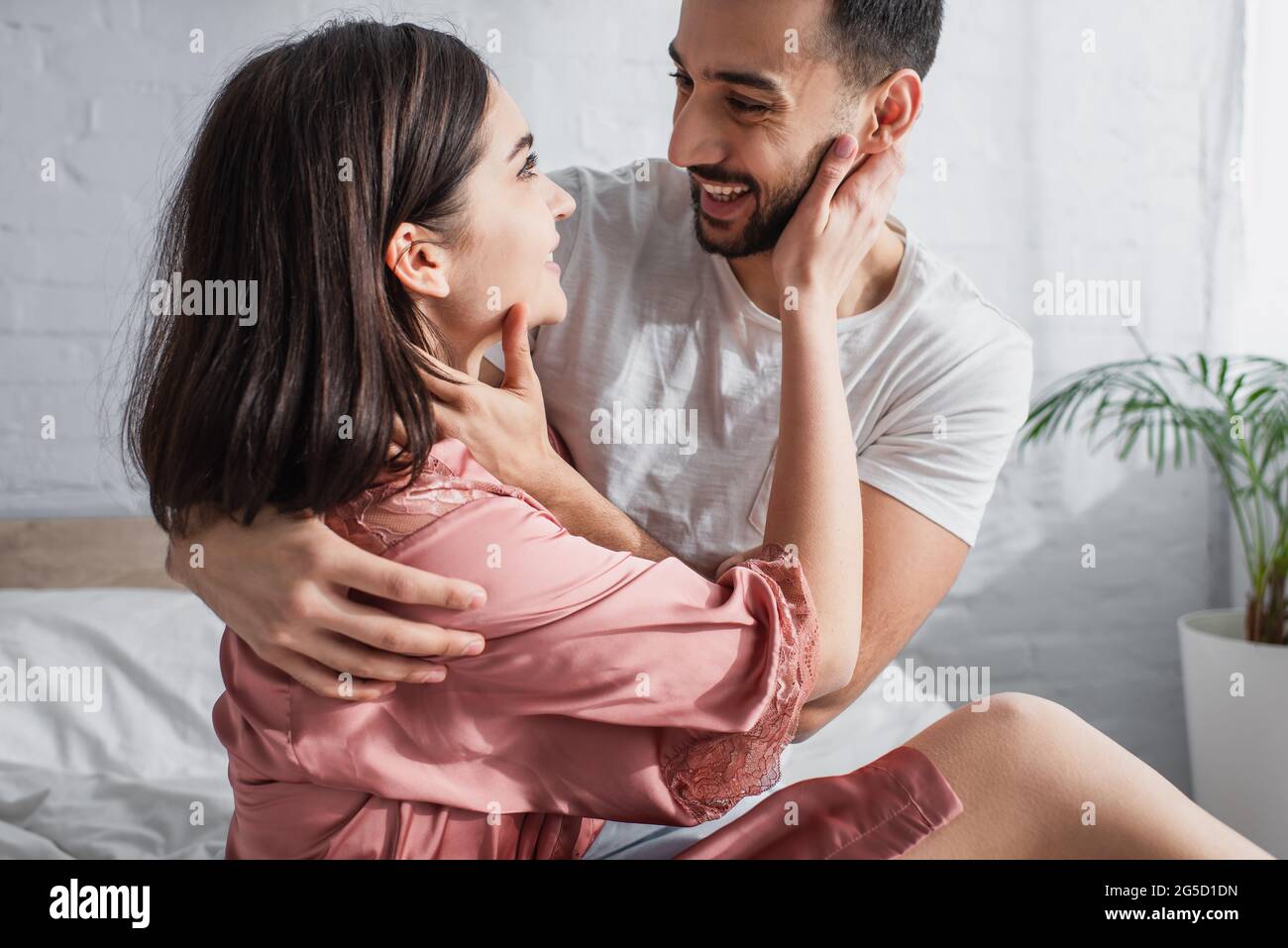 smiling young man gently hugging and touching face of girlfriend in ...