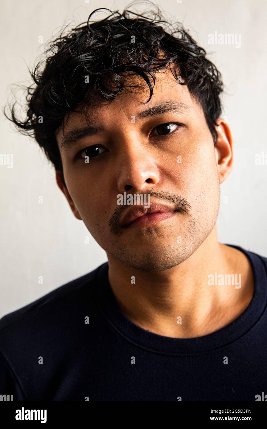 A confident and attractive Thai man poses for a portrait with serious ...