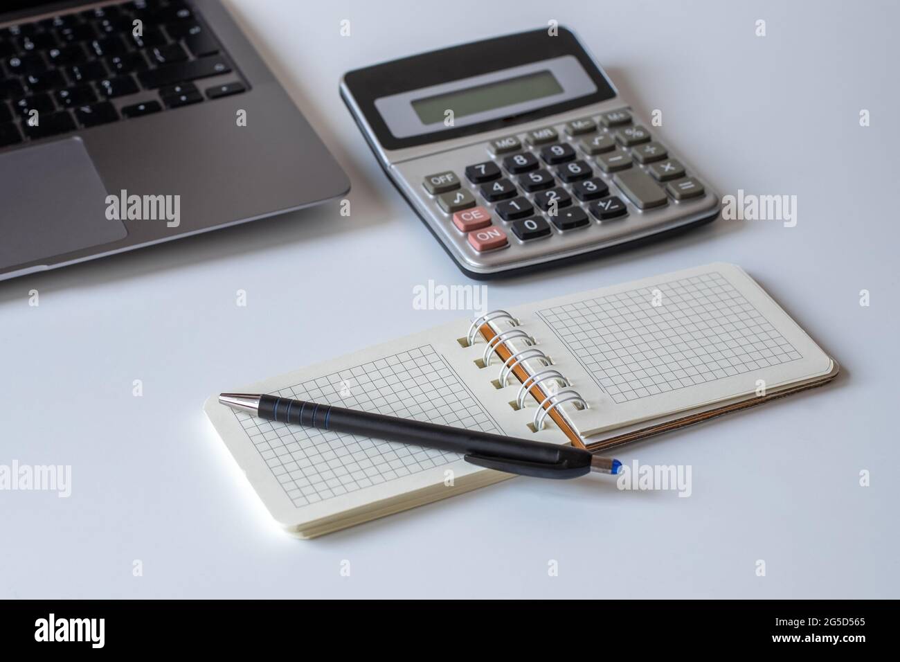 Office desk with spiral notepad, calculator, pen and laptop on white ...