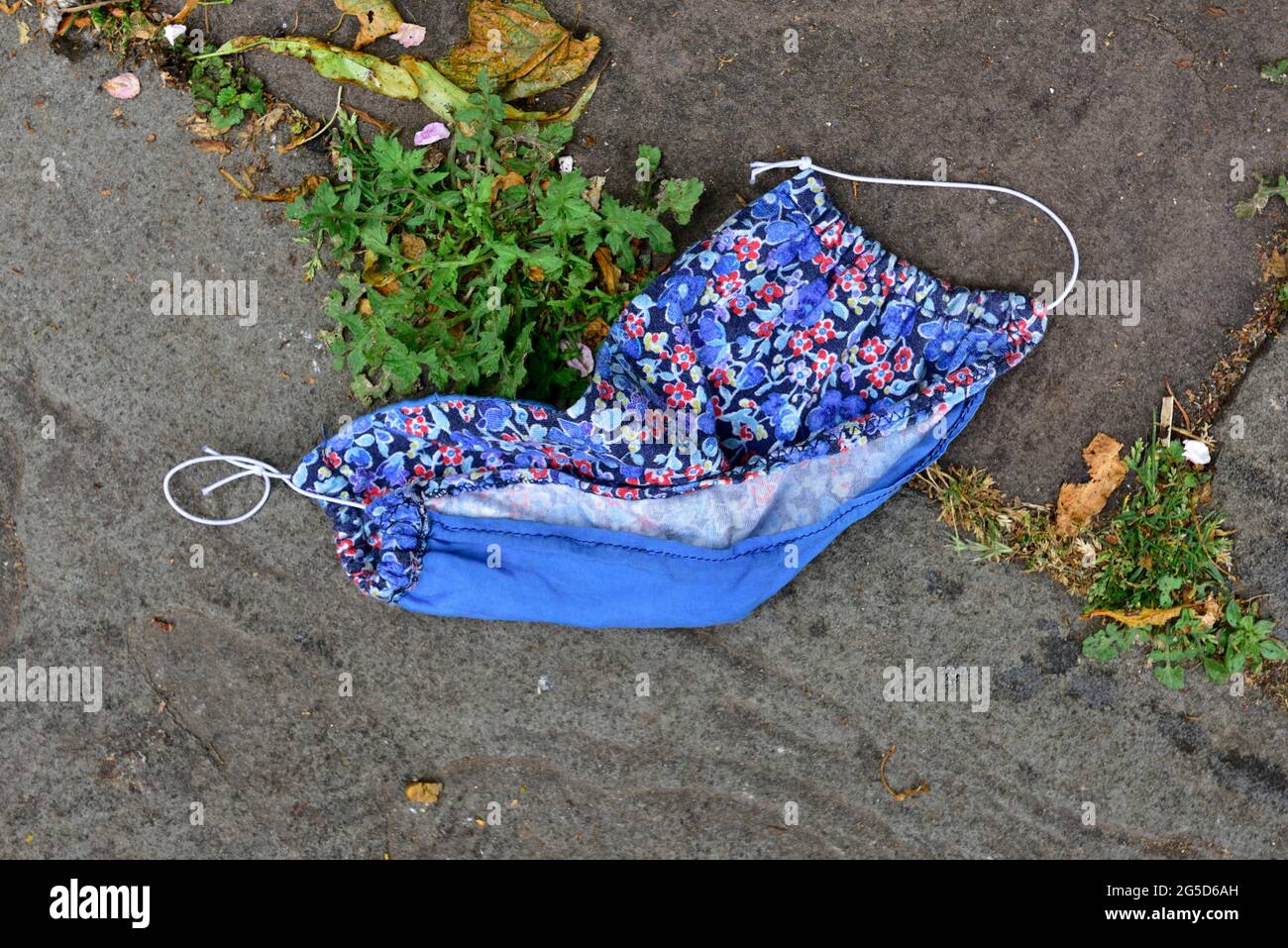 Colourful face mask discarded on pavement as environmental waste Stock ...