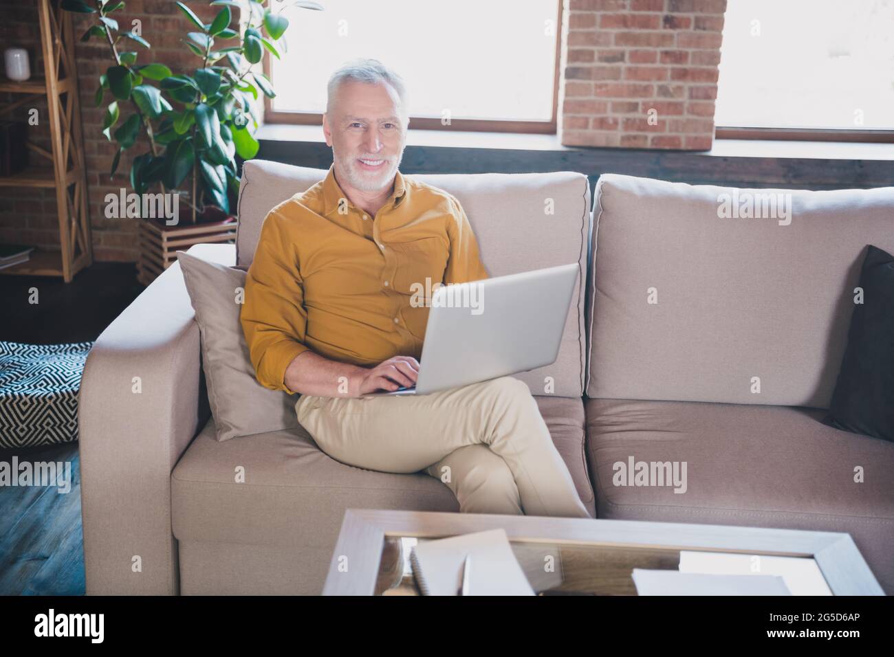 Portrait of cheerful man sit on sofa hold laptop beaming smile look ...