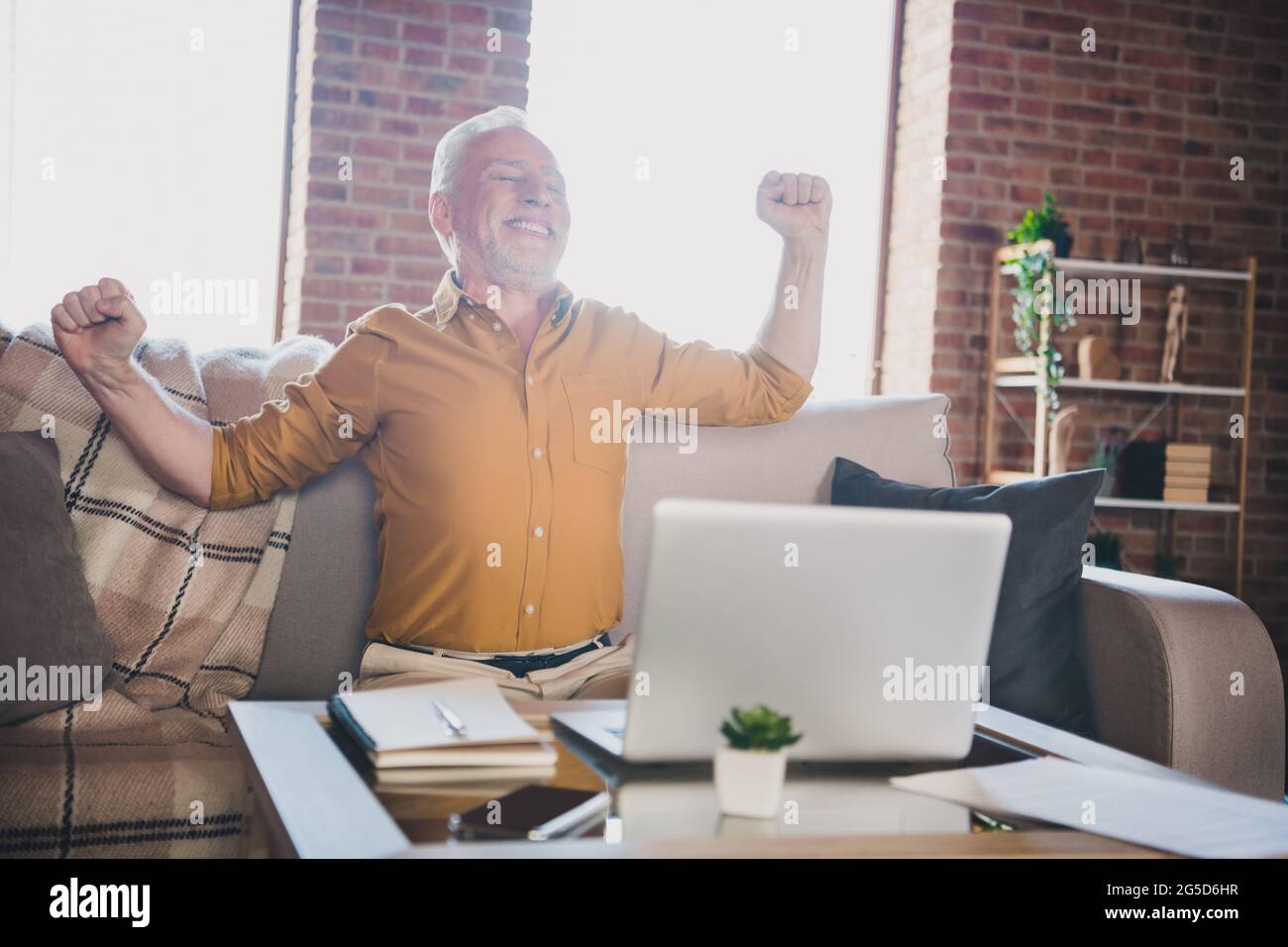Portrait of handsome man sit on sofa closed eyes toothy smile stretch ...