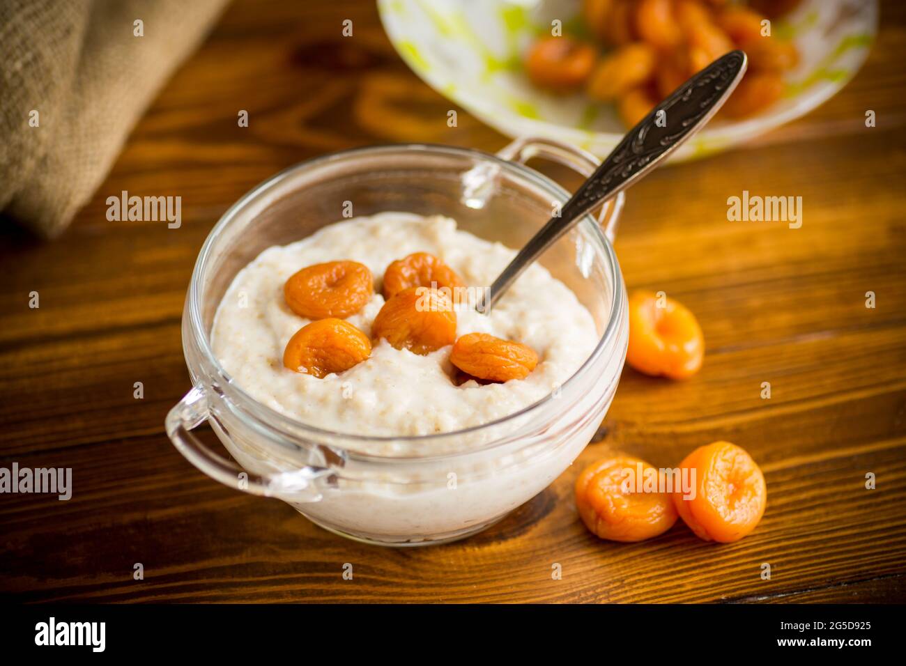 cooked boiled sweet oatmeal with dried apricots in a bowl on a wooden ...