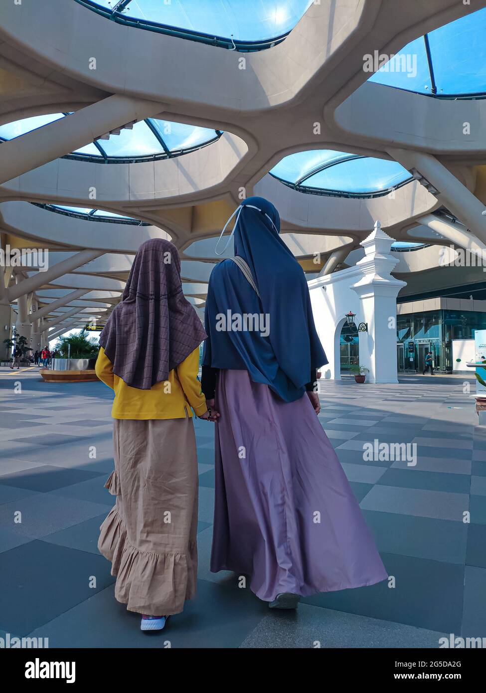 Back view of two Muslim women with hijabs walking together in the city ...