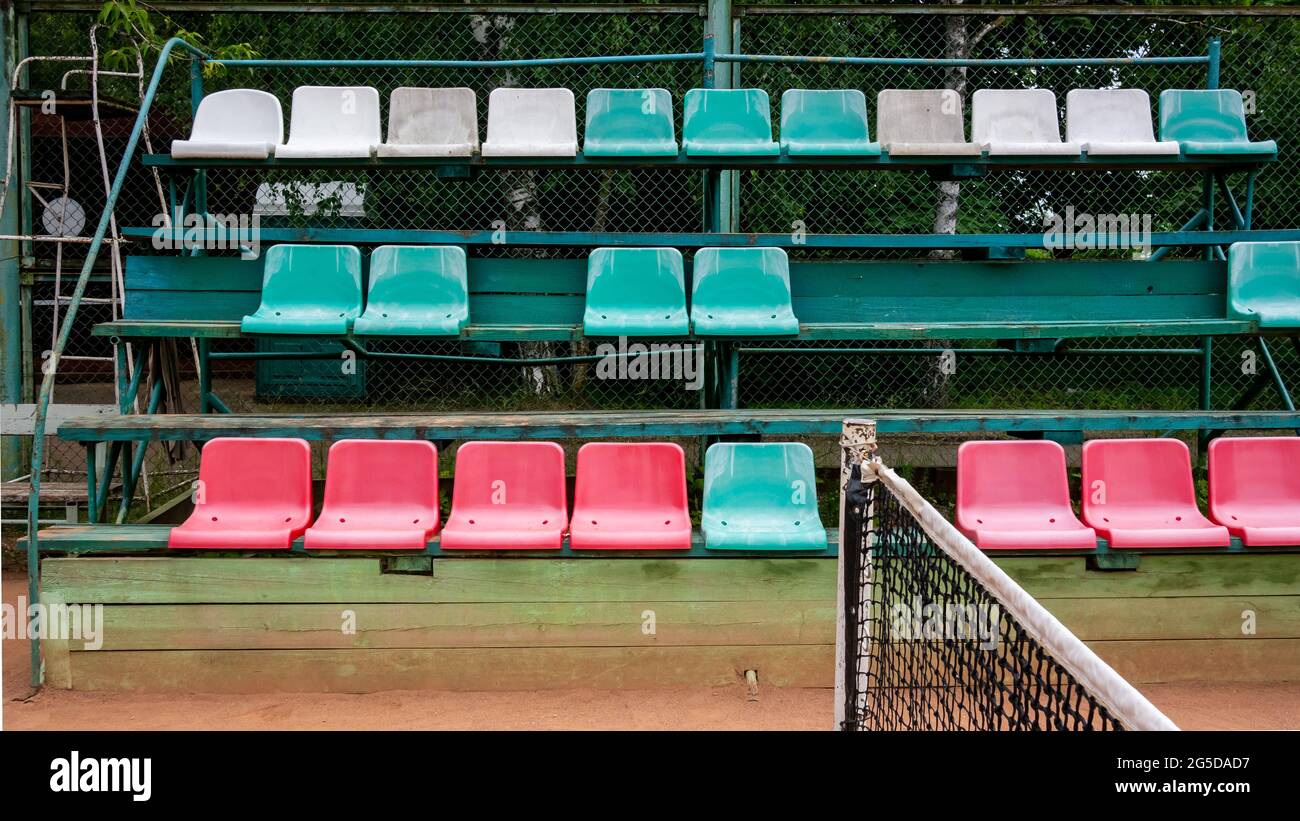 Empty rows of simple plastic green, white and red vintage seats at the ...