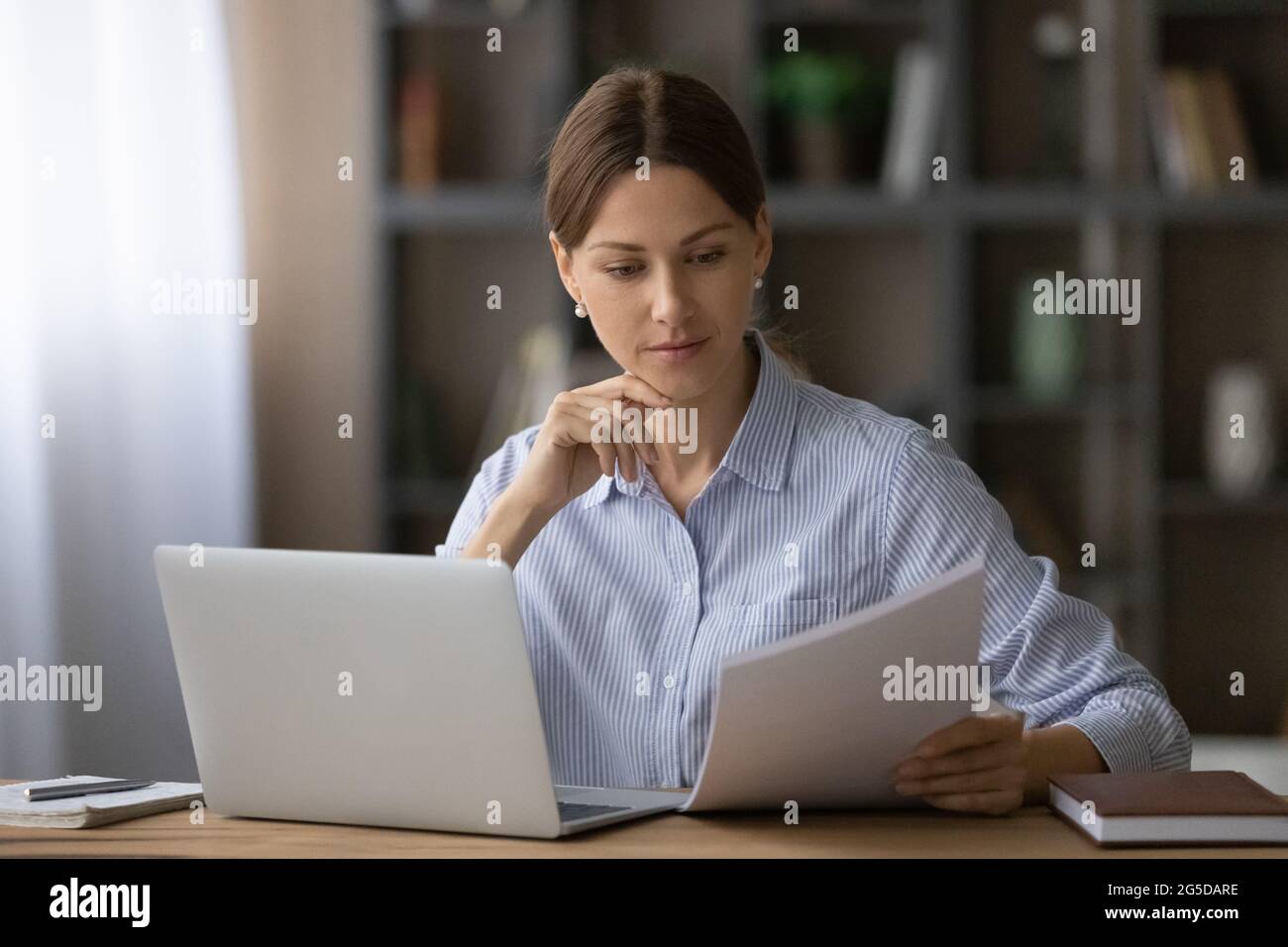 Concentrated young female manager analyzing paper document Stock Photo ...