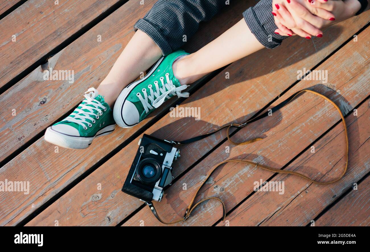 Female legs in hipster sneakers and retro camera on wooden surface ...