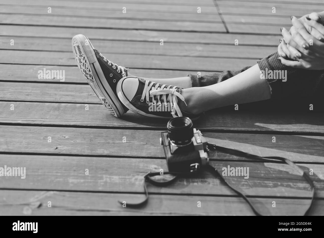 Female legs in hipster sneakers and retro camera on wooden surface ...