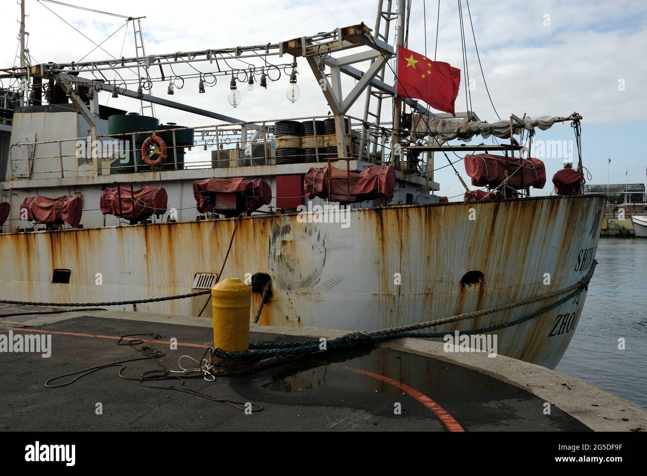 A ship with rust marks docked at harbour with the flag of China Stock ...