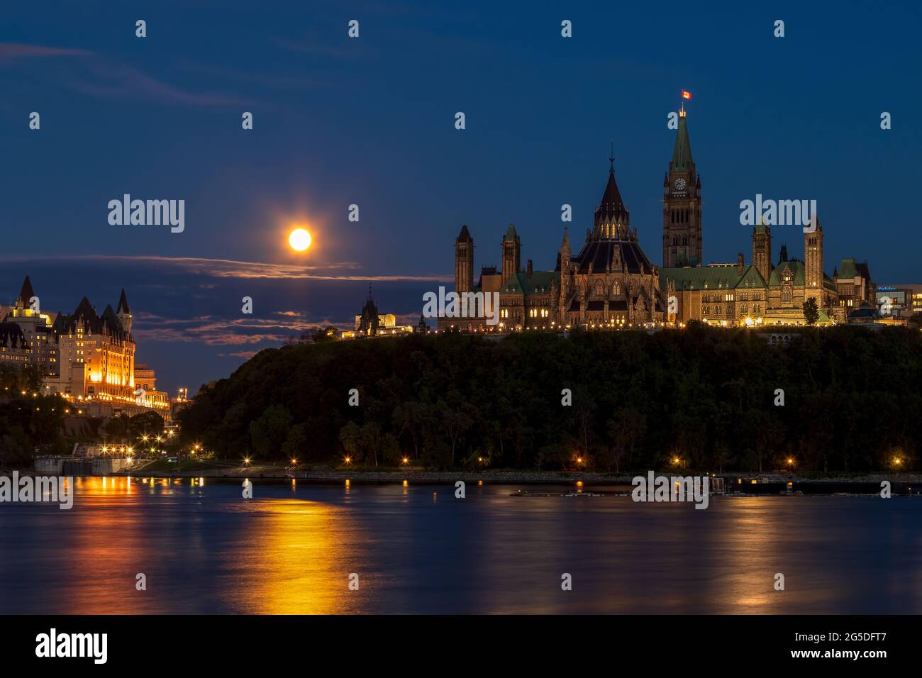 Downtown Ottawa at night by the river. Full moon shining low in the ...