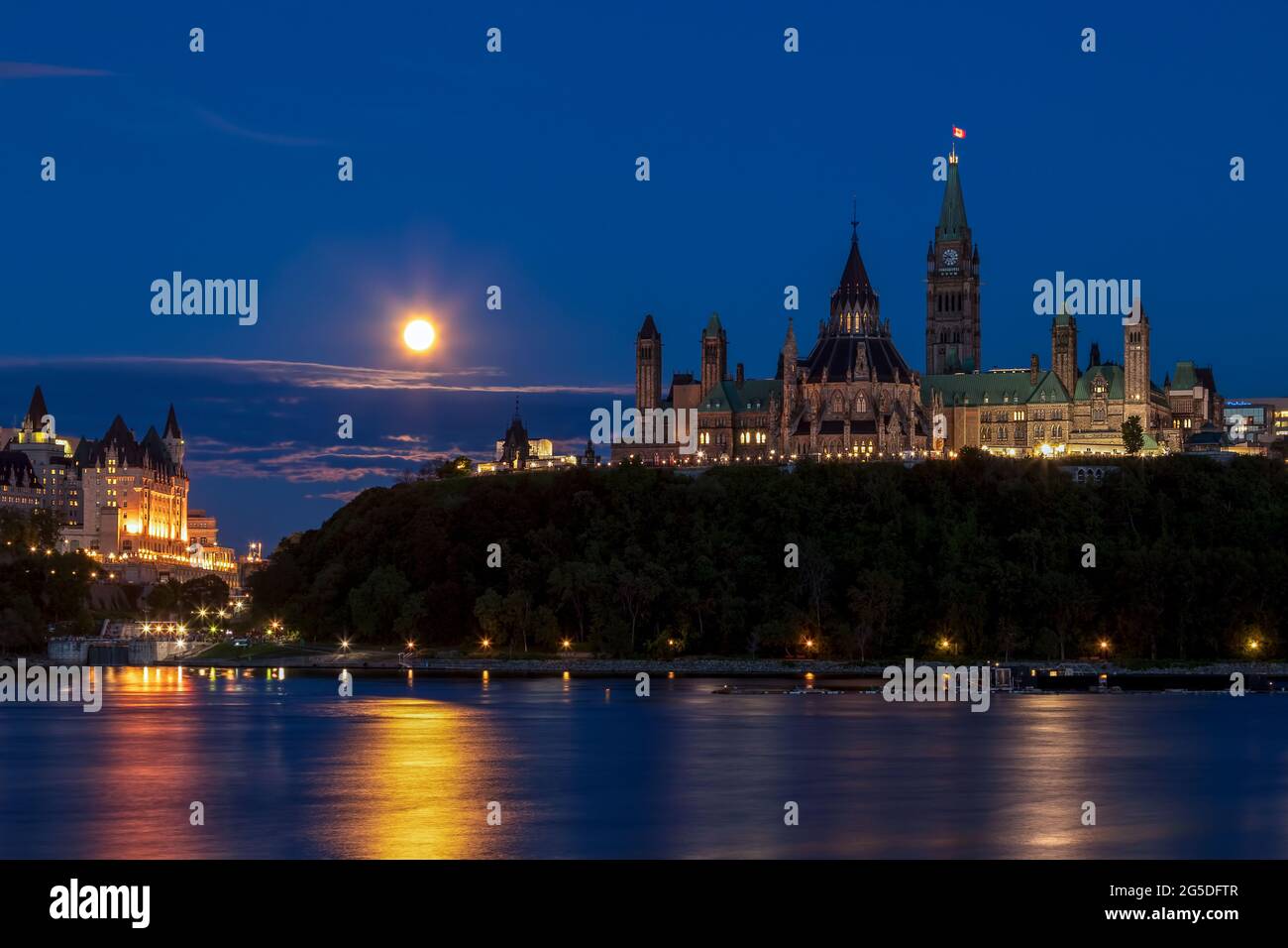 Downtown Ottawa at night by the river. Full moon shining low in the ...
