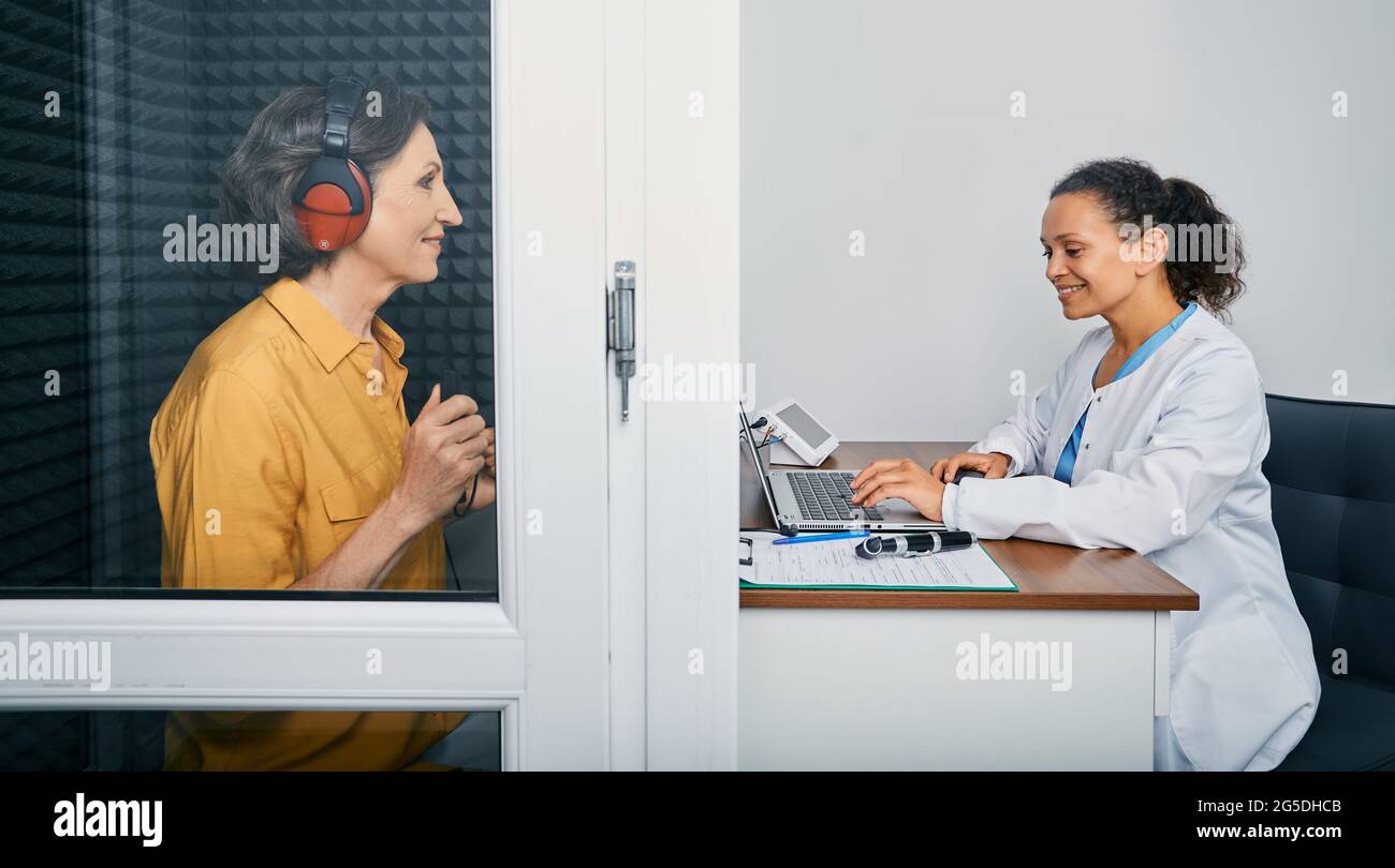 Audiological exam. Audiologist doing hearing check-up to a senior ...