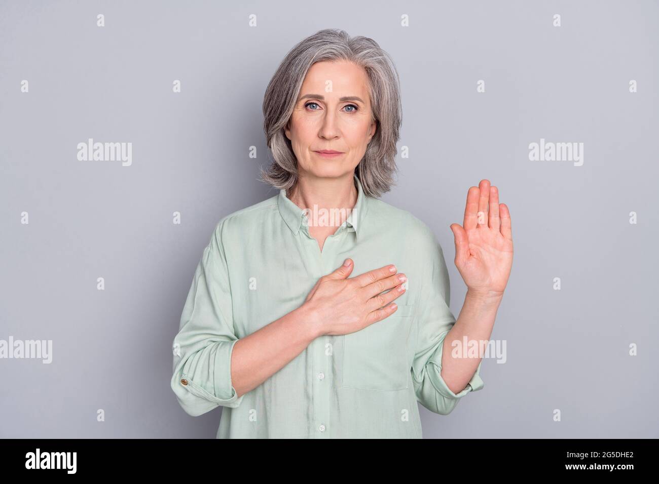 Photo of serious mature woman grandmother hold hand chest giving oath ...