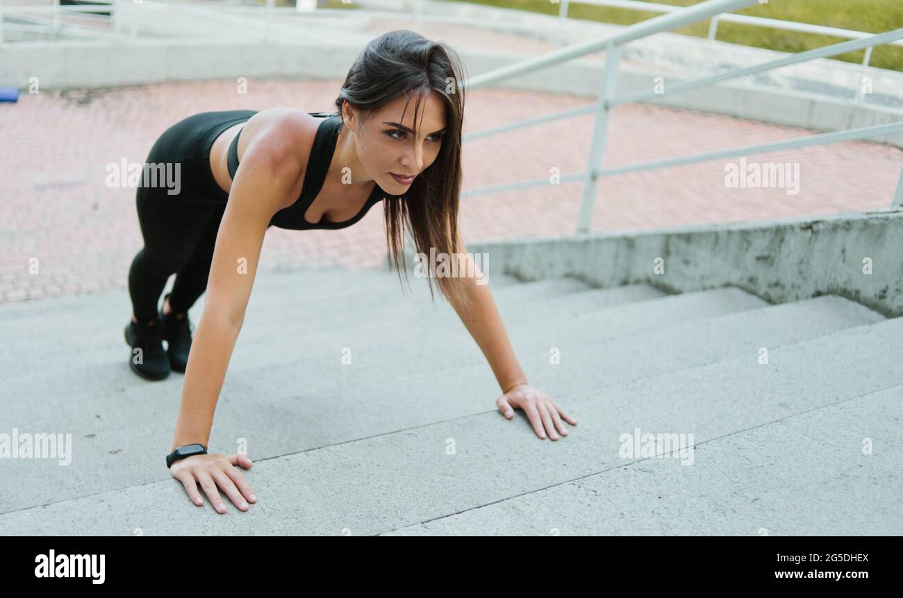 Young fit woman doing push up exercise from stairs outdoors in an urban ...