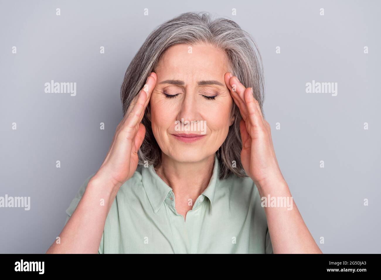 Portrait of attractive depressed gray-haired woman having headache ...