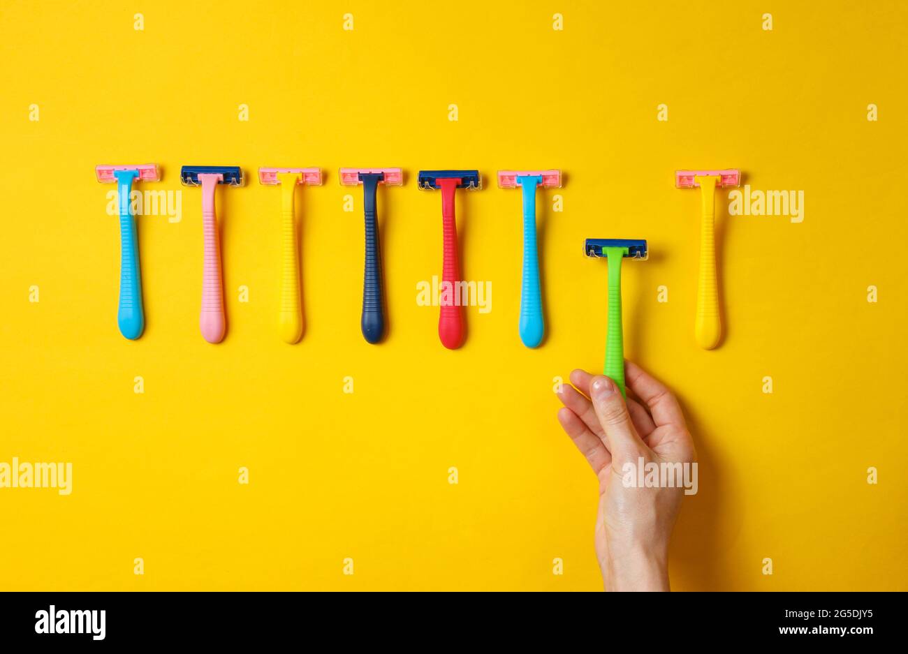 Female hand choosing green razor among a variety of colored epilator ...