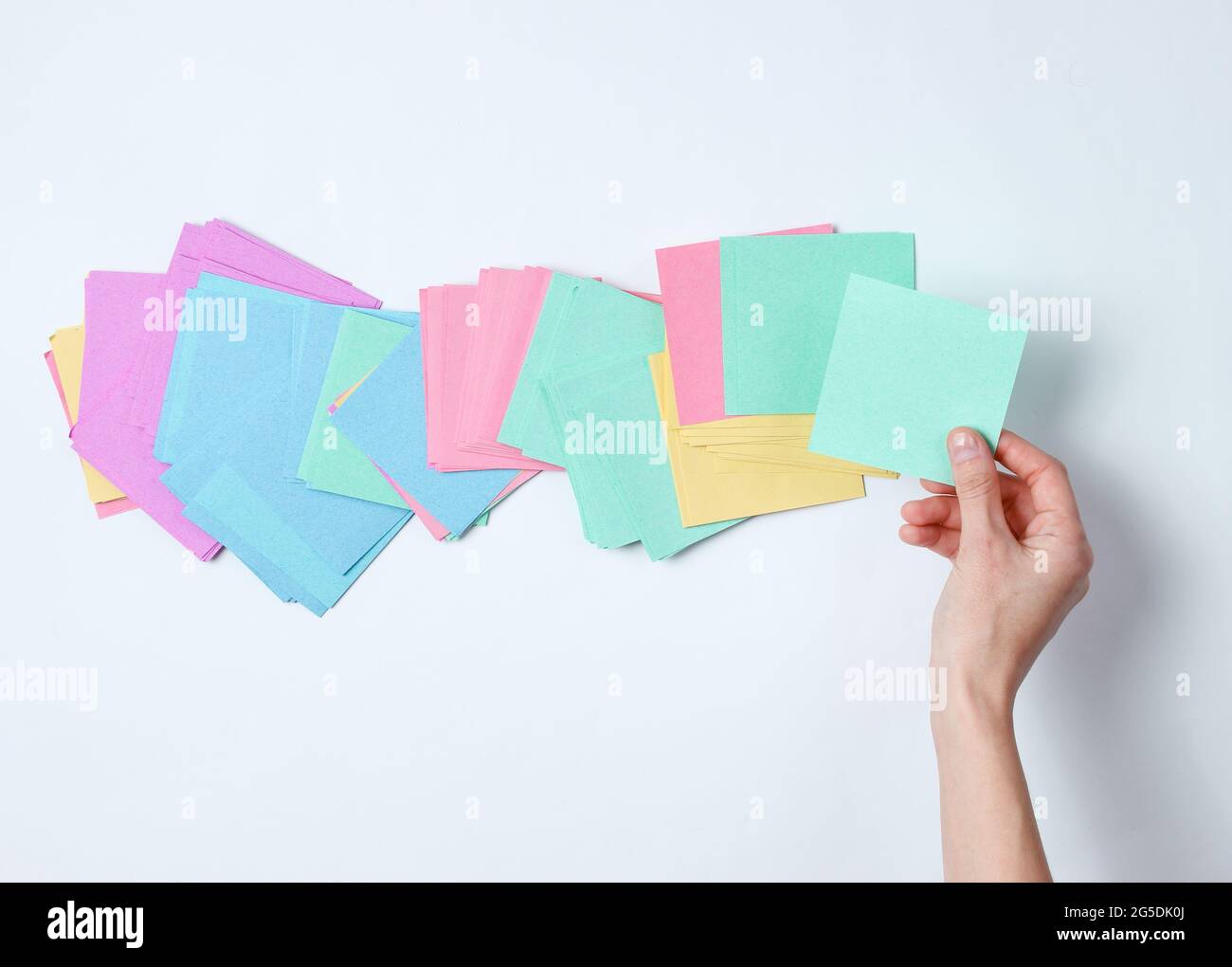 Female hand holding blue memo sheet of paper on white background. Top ...