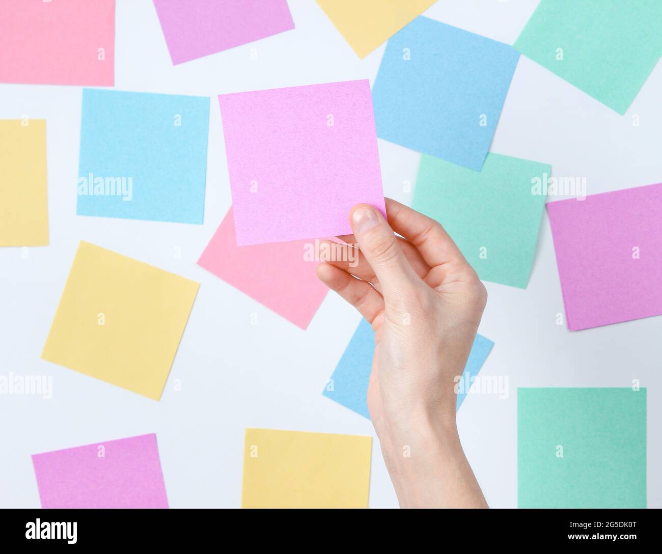 Female hand holding pink memo sheet of paper on a white background ...