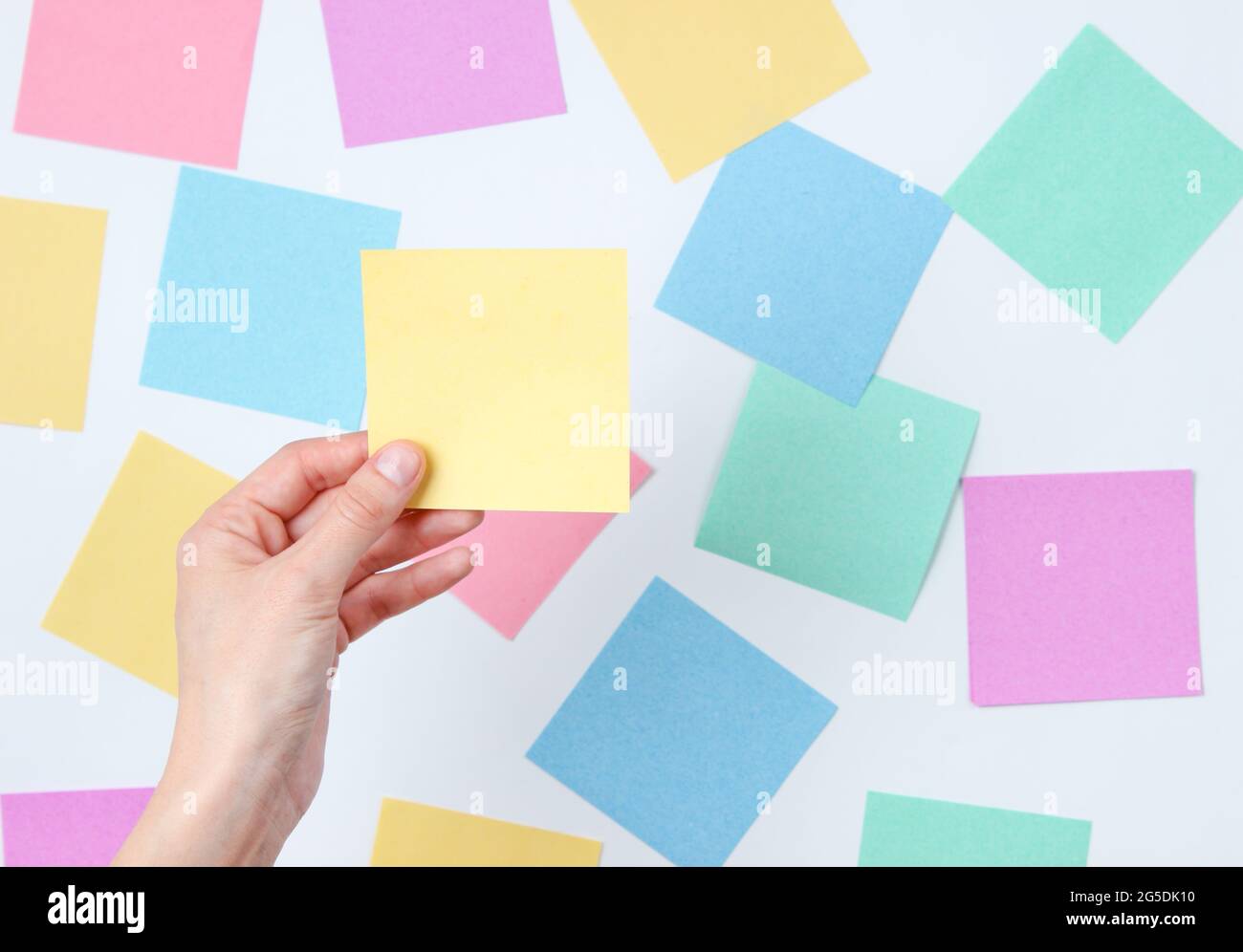 Female hand holding yellow memo sheet of paper on a white background ...