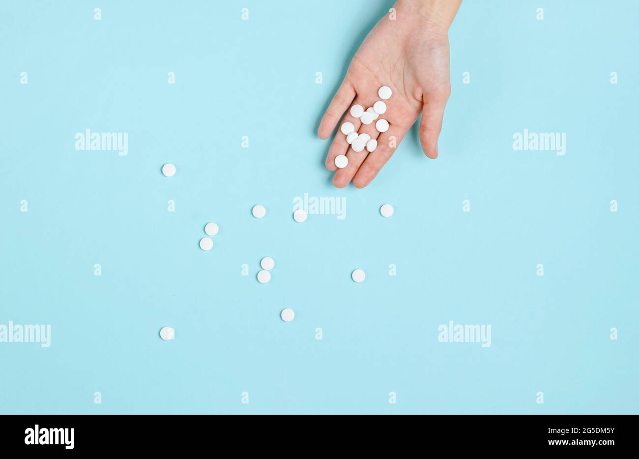 Many white tablets in the palm of hand on blue background. Medical ...