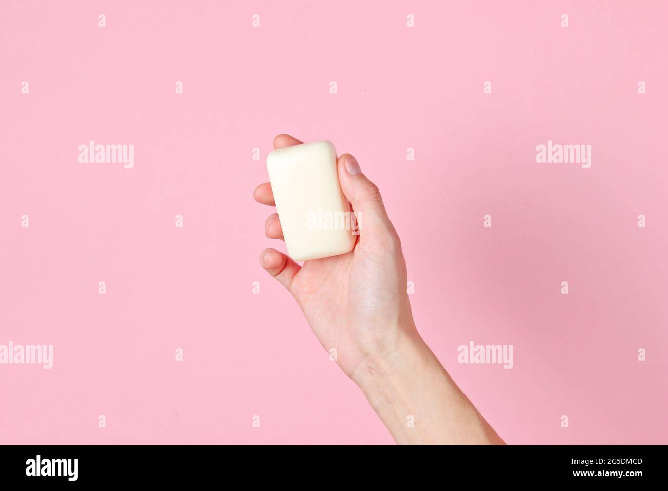 Female hand holding piece of soap against pink background. Top view ...