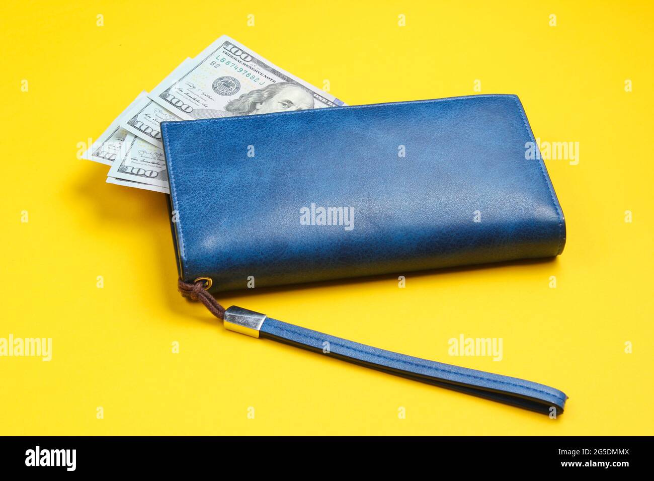 Leather purse and hundred dollar bills on yellow background ...