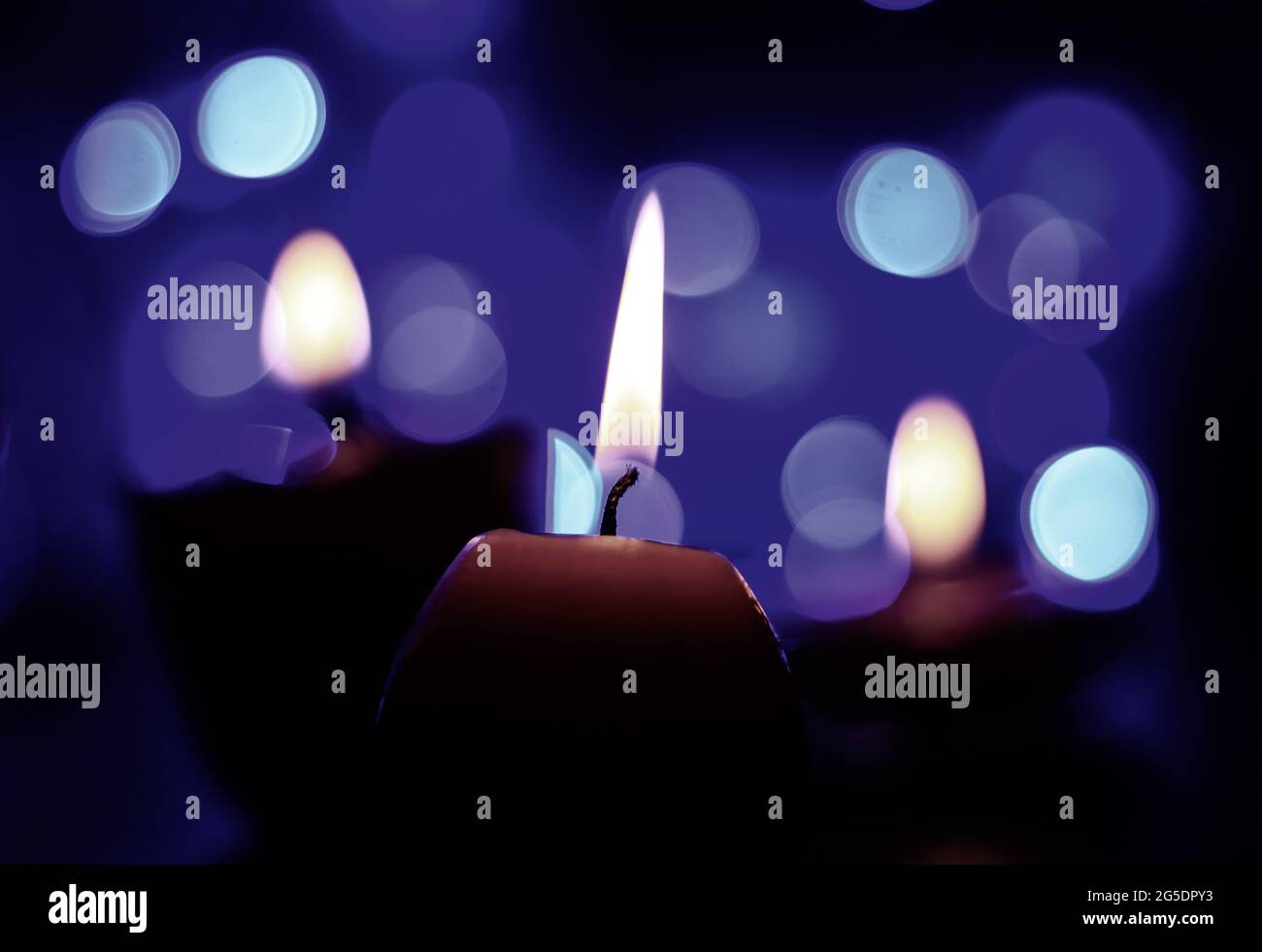 Candle lights in darkness with colorful light effects and bokeh for ...