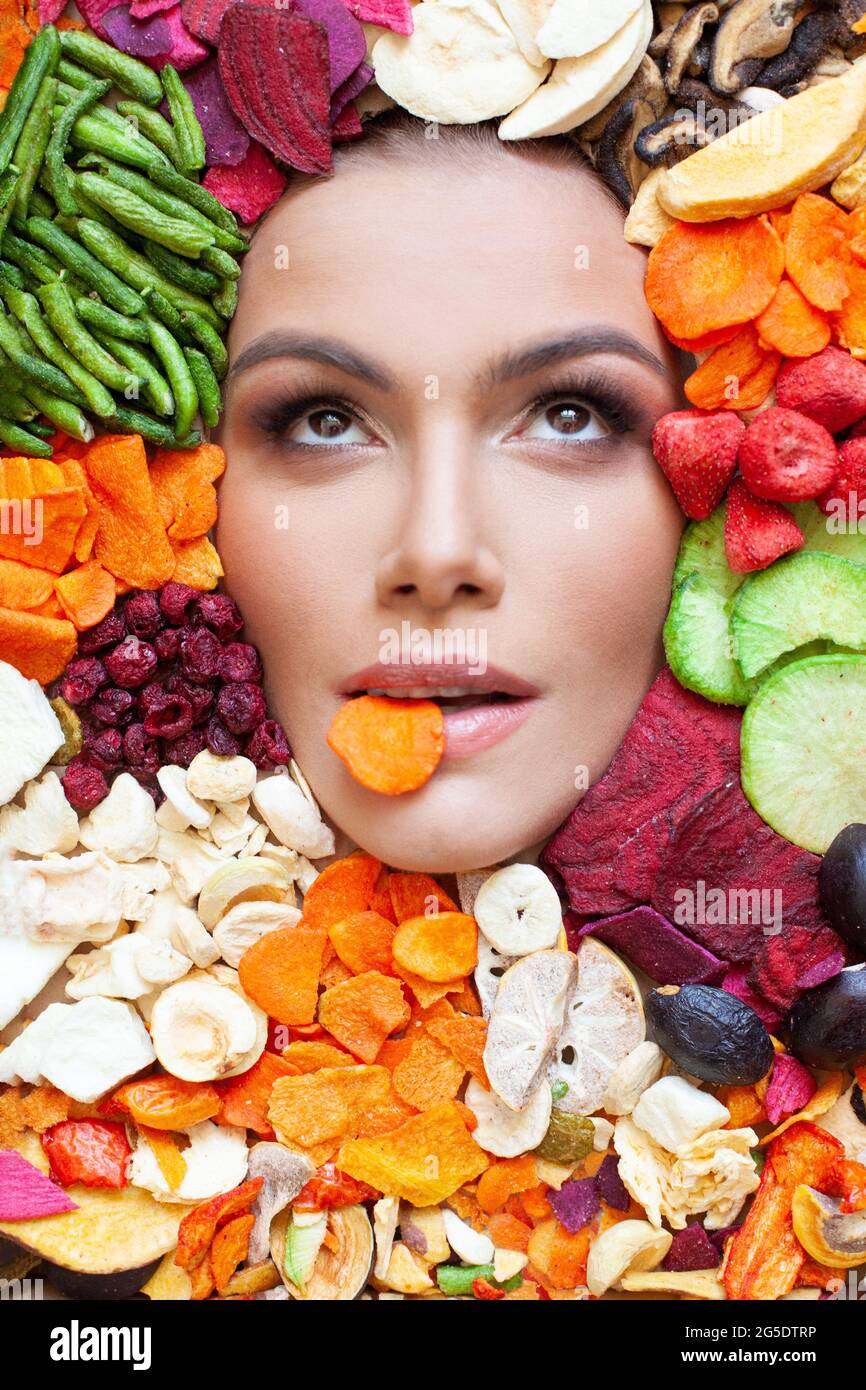 Attractive woman face on bright colorful organic fruits and vegetables ...