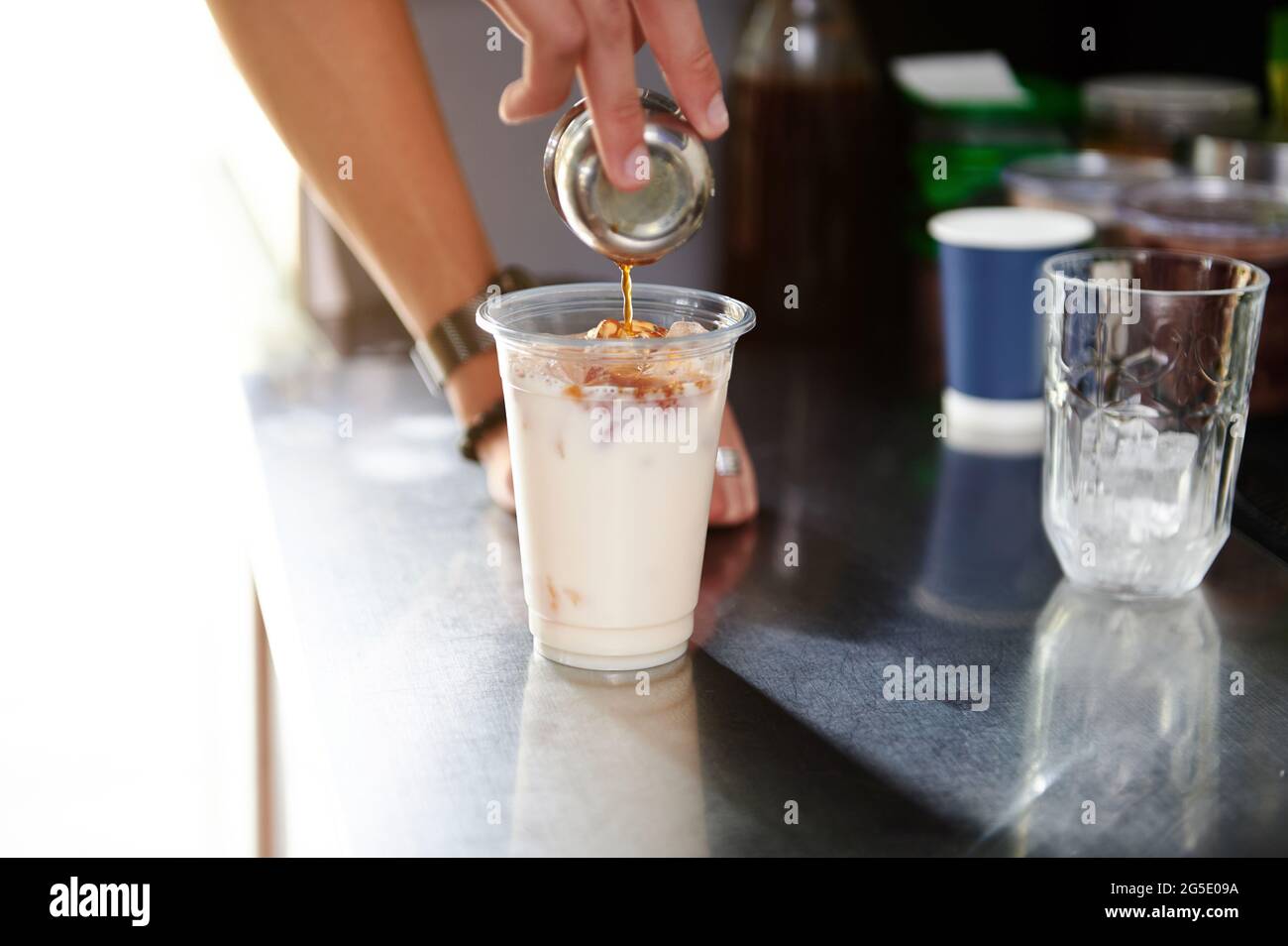 Barista hands pouring a caramel sauce into a whipped milkshake to ...