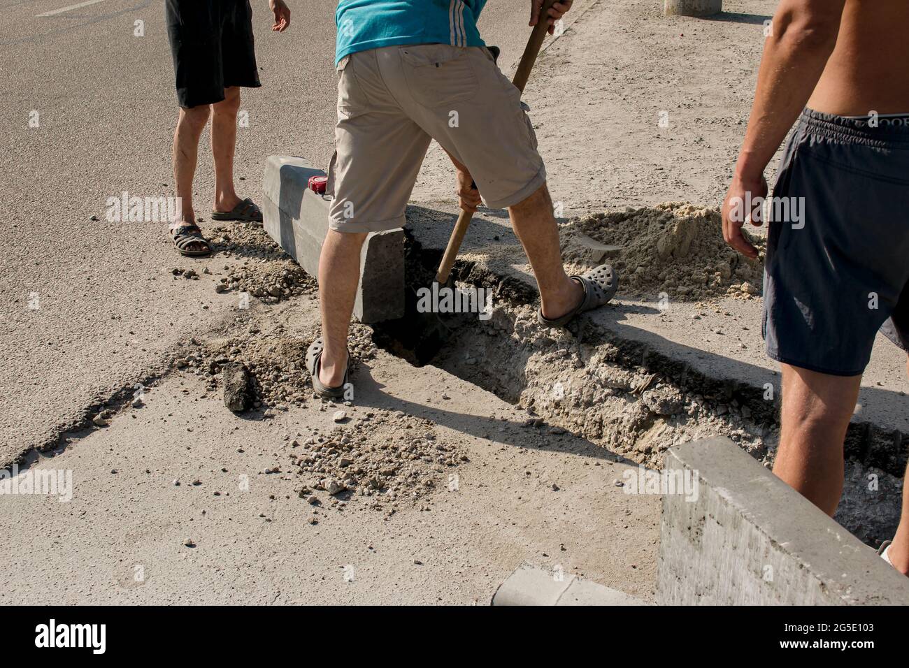 The process of laying the sidewalk curb. Workers place a deflected ...