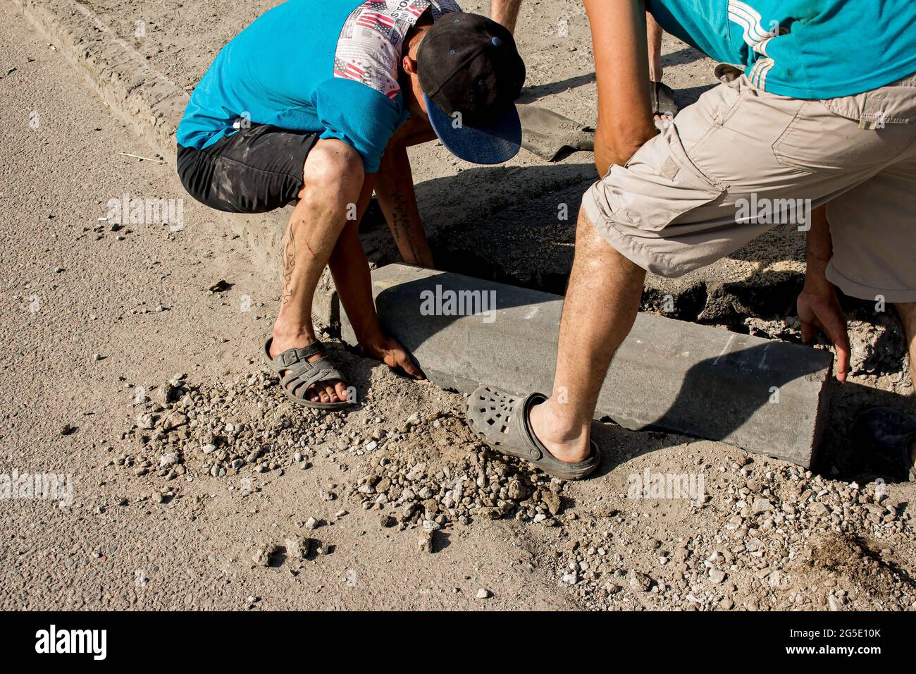 The process of laying the sidewalk curb. Workers place a deflected ...