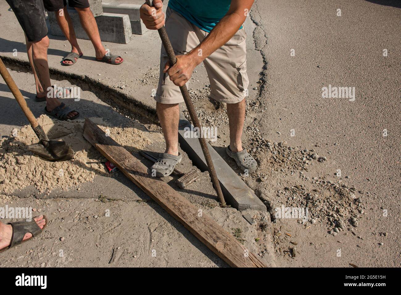 The process of laying the sidewalk curb. Workers place a deflected ...