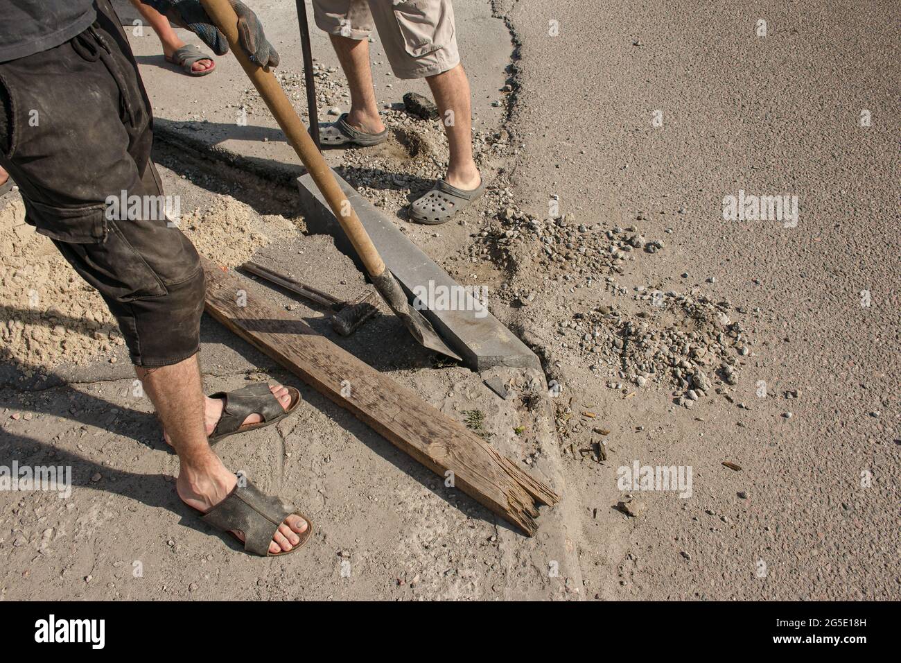 The process of laying the sidewalk curb. Workers place a deflected ...