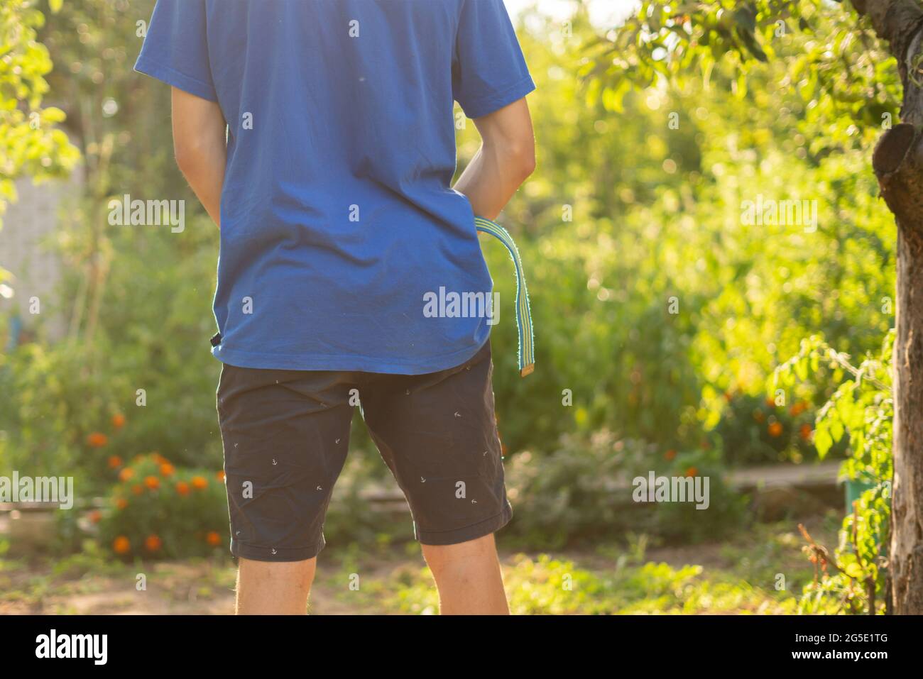 rear view of young person standing outdoor and piss under the tree ...