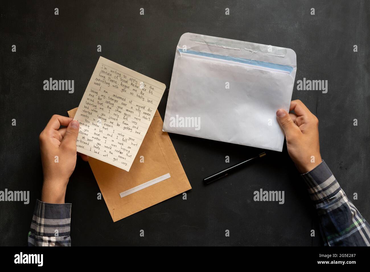 person put a paper into the envelope to send it to friend, top view ...