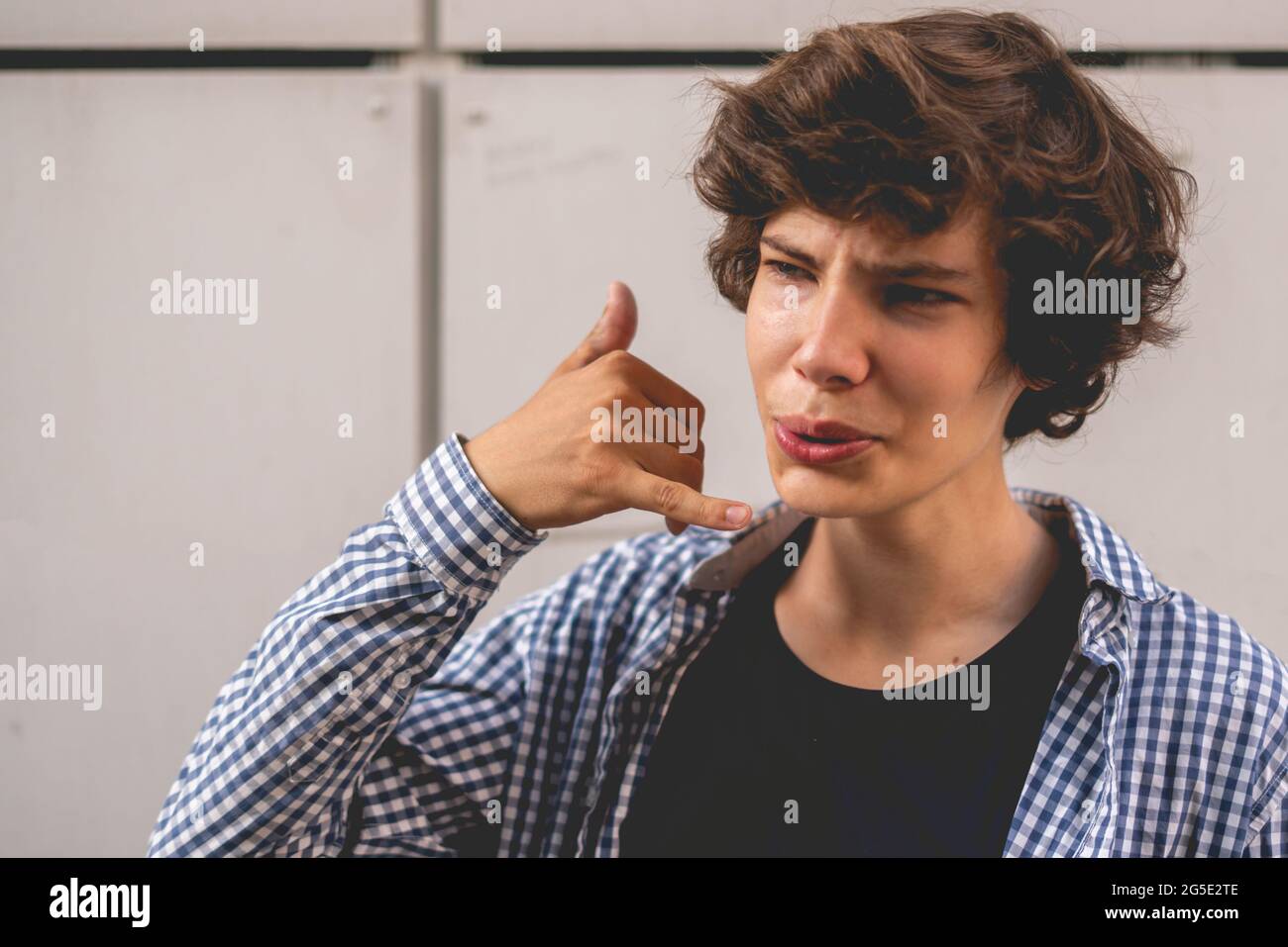 young guy showing a call me sign gesture finger, symbol of mobile phone ...