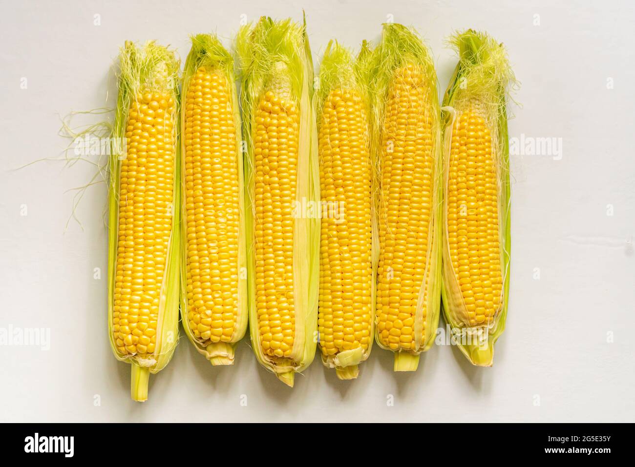 top view set of raw fresh corns with skin on color surface Stock Photo ...
