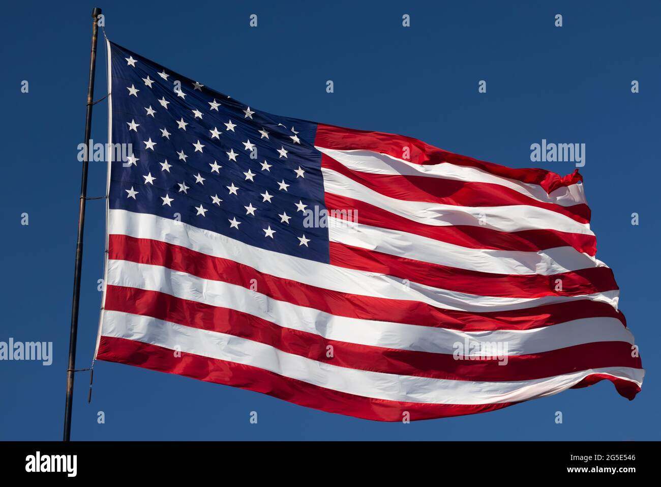 American Flag Waving In Wind Against a Deep Blue Sky Stock Photo - Alamy