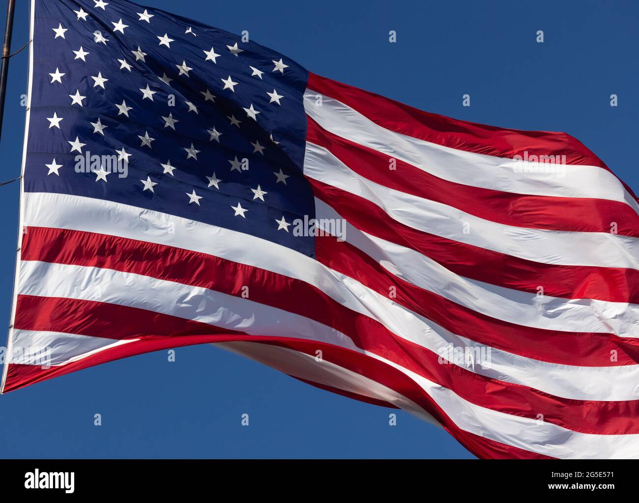 American Flag Waving In Wind Against a Deep Blue Sky Stock Photo - Alamy