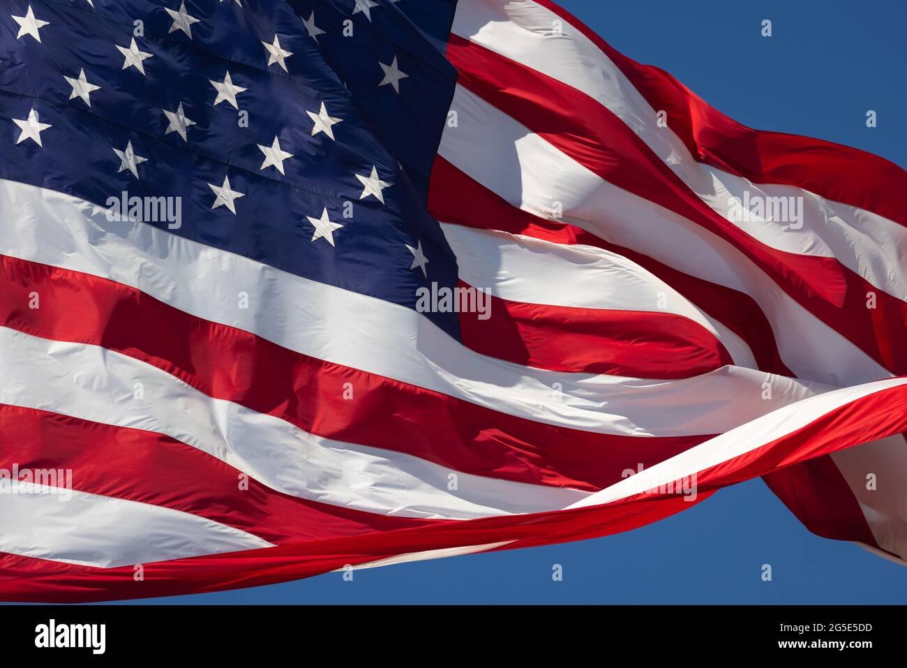 American Flag Waving In Wind Against a Deep Blue Sky Stock Photo - Alamy
