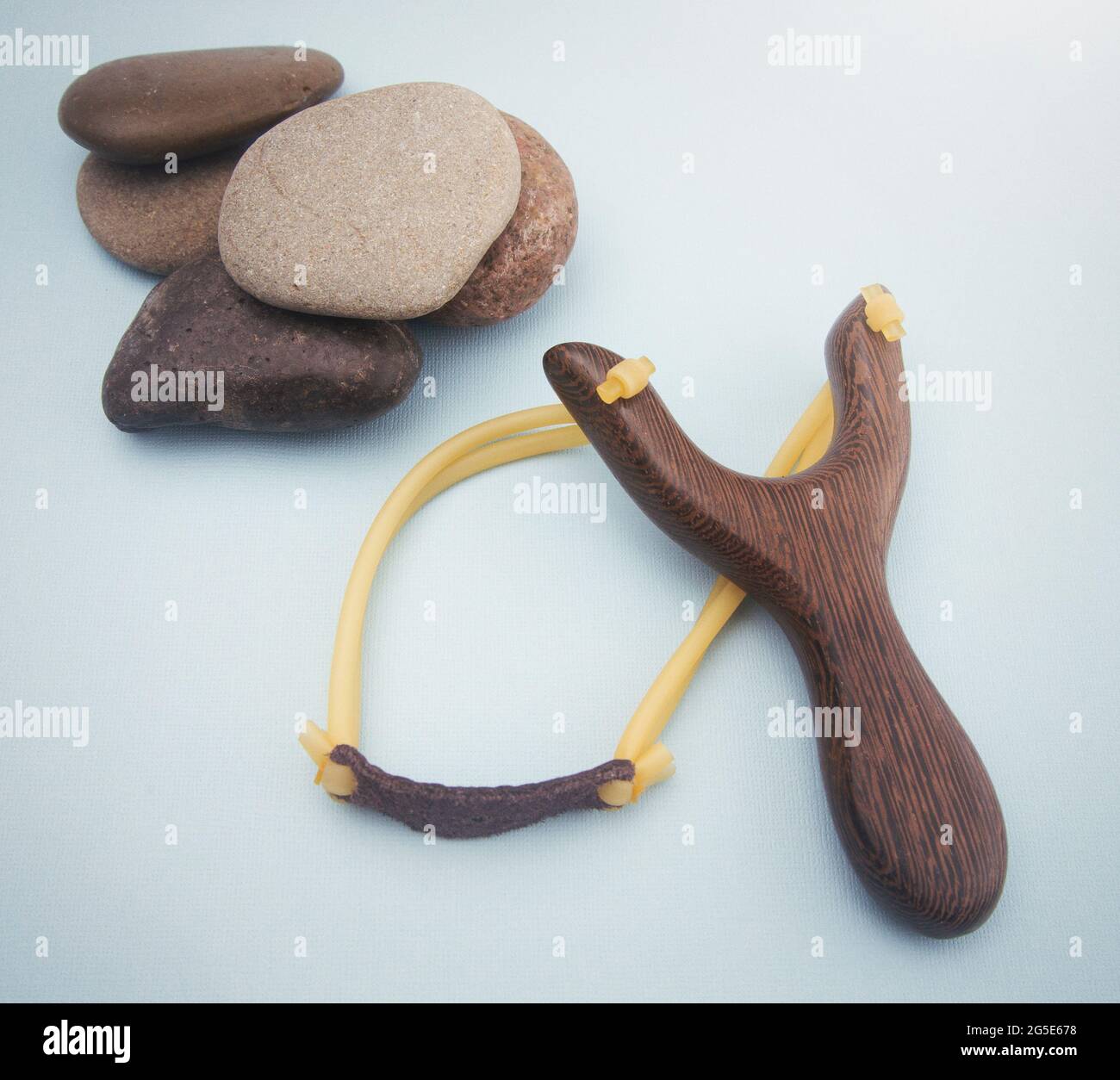 Slingshot and Five Smooth Stones on a Blue Table Stock Photo - Alamy