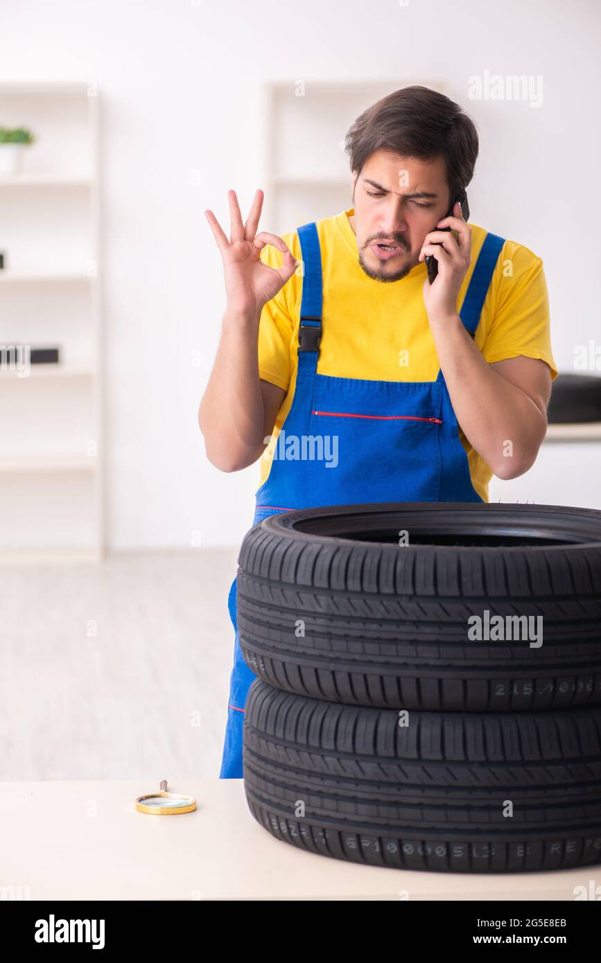 Young garage worker with tyre at workshop Stock Photo - Alamy