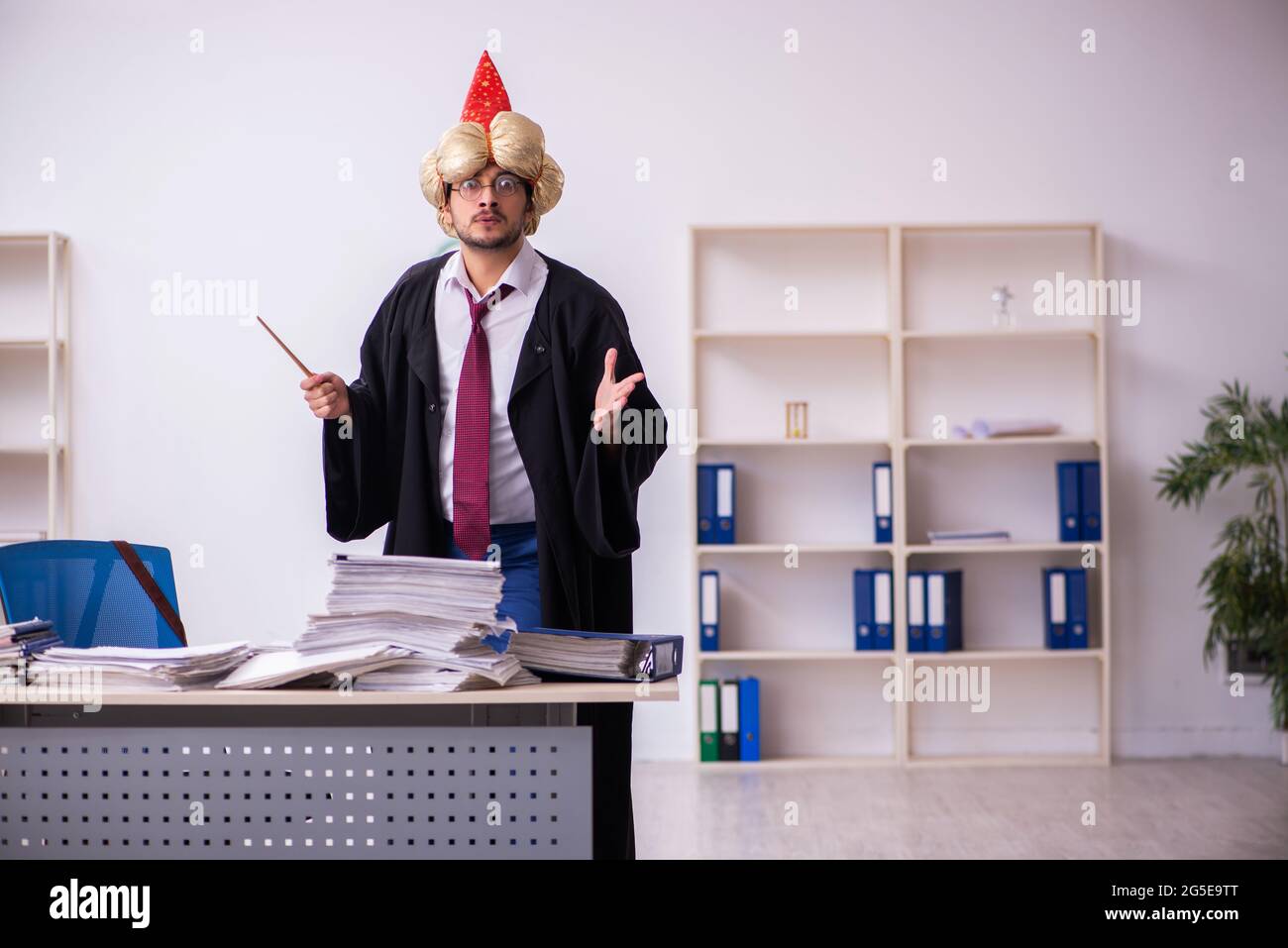 Funny young employee magician and too much work in the office Stock ...
