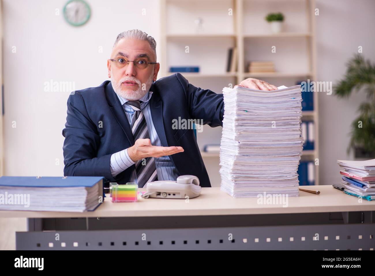 Old male employee unhappy with excessive work at workplace Stock Photo ...