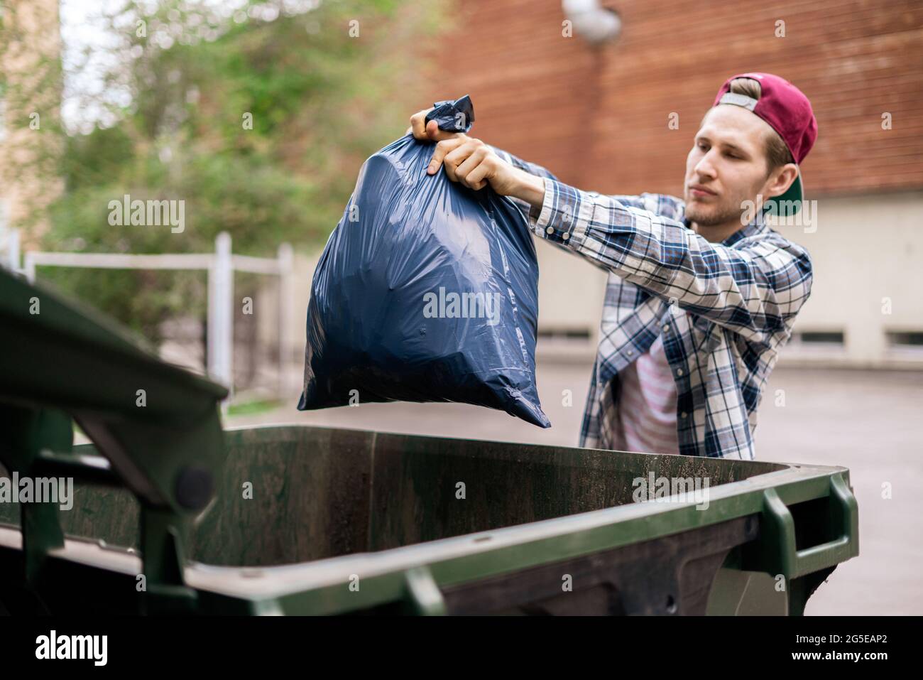 male dumping waste package into a big trash bin container Stock Photo ...