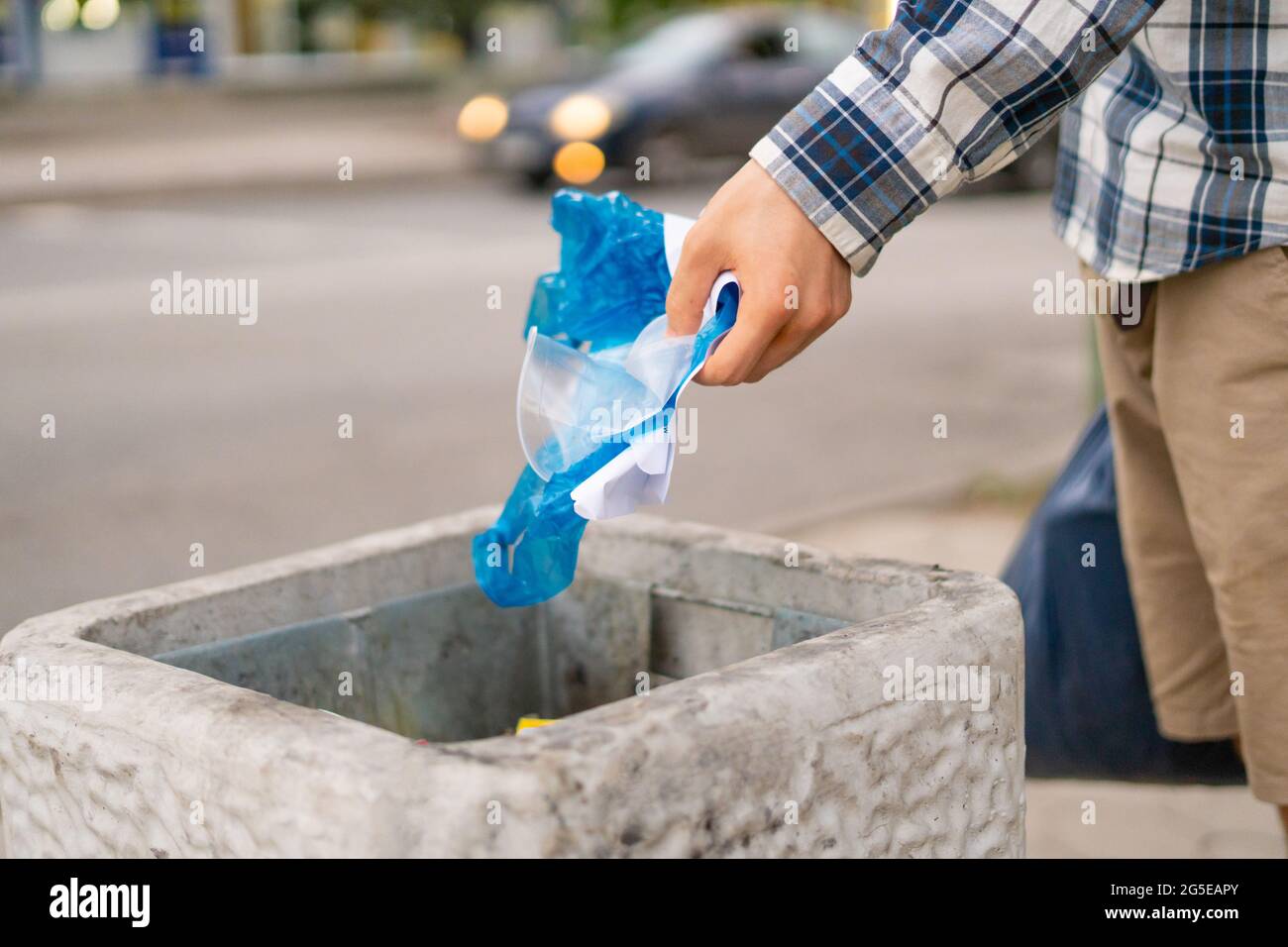 hand throwing paper and plastic garbage into a trash urn in the city ...