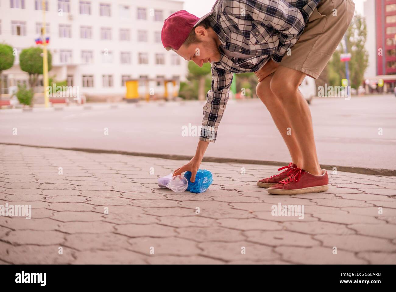 man picks the garbage plastic and paper in the city street for clean ...