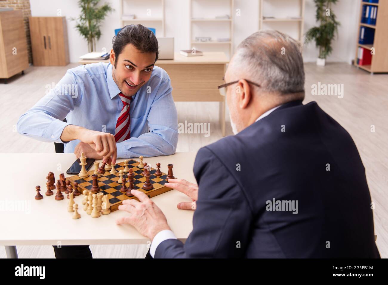 Two male employees playing chess at workplace Stock Photo - Alamy